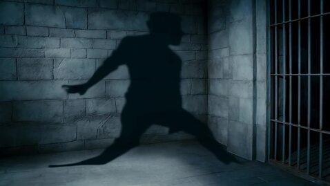 A prison cell. A prisoner dances - his shadow on